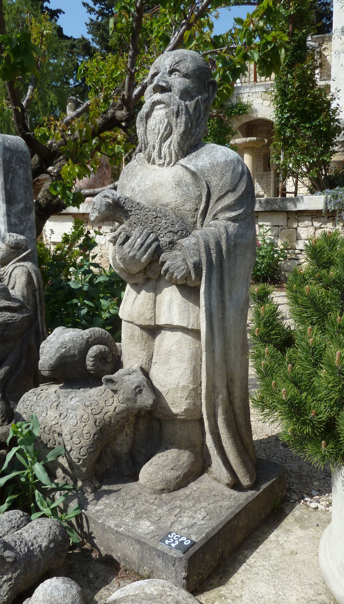 Statue de jardin en sculpture de pierre d'un berger et de ses moutons.